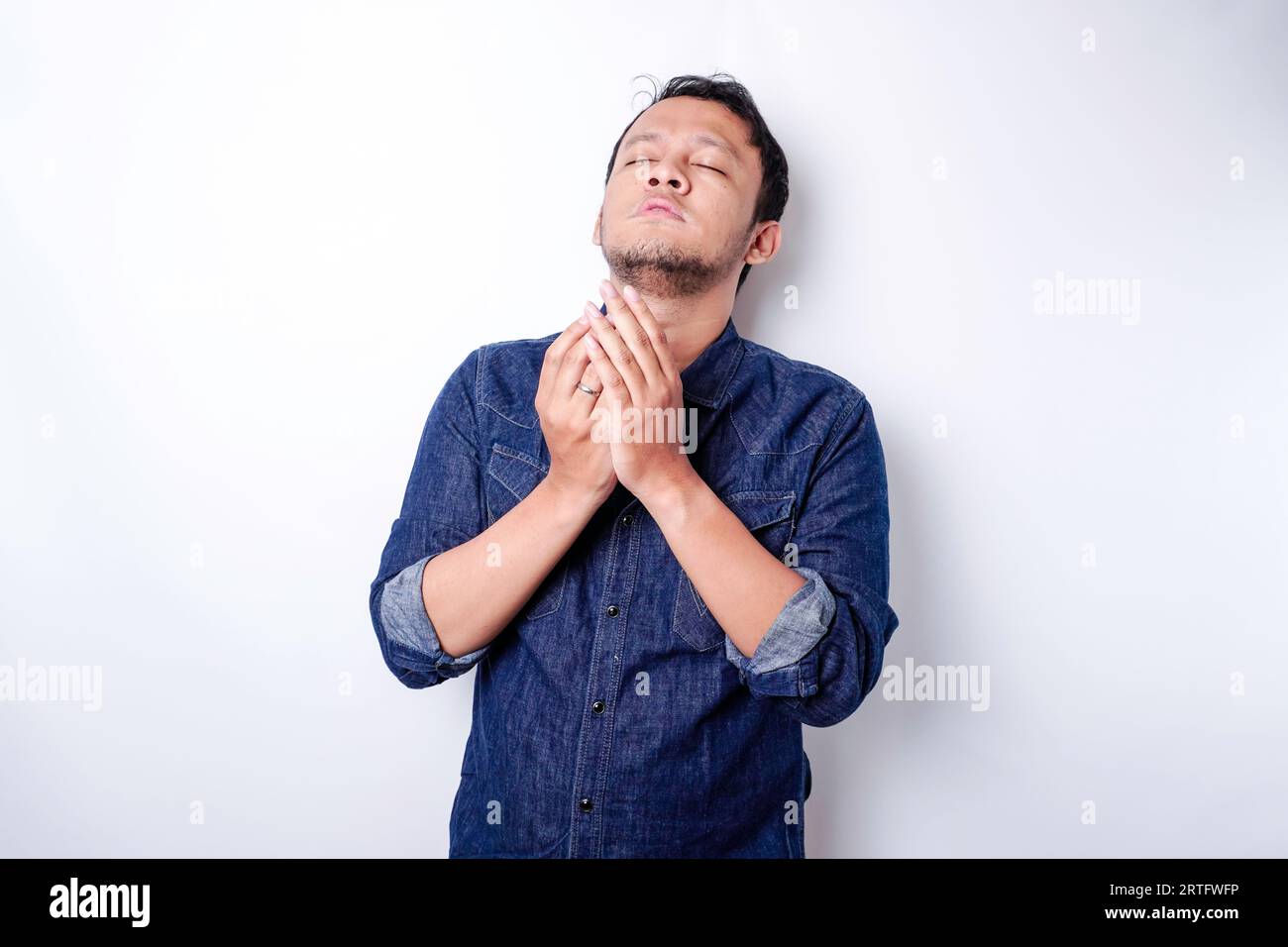 Calm spiritual handsome Asian guy praying with closed eyes. Serious ...