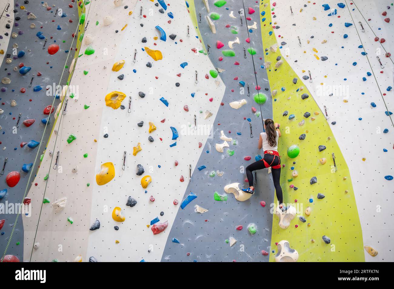Rock climber young woman hanging on colored hooks on climbing ...