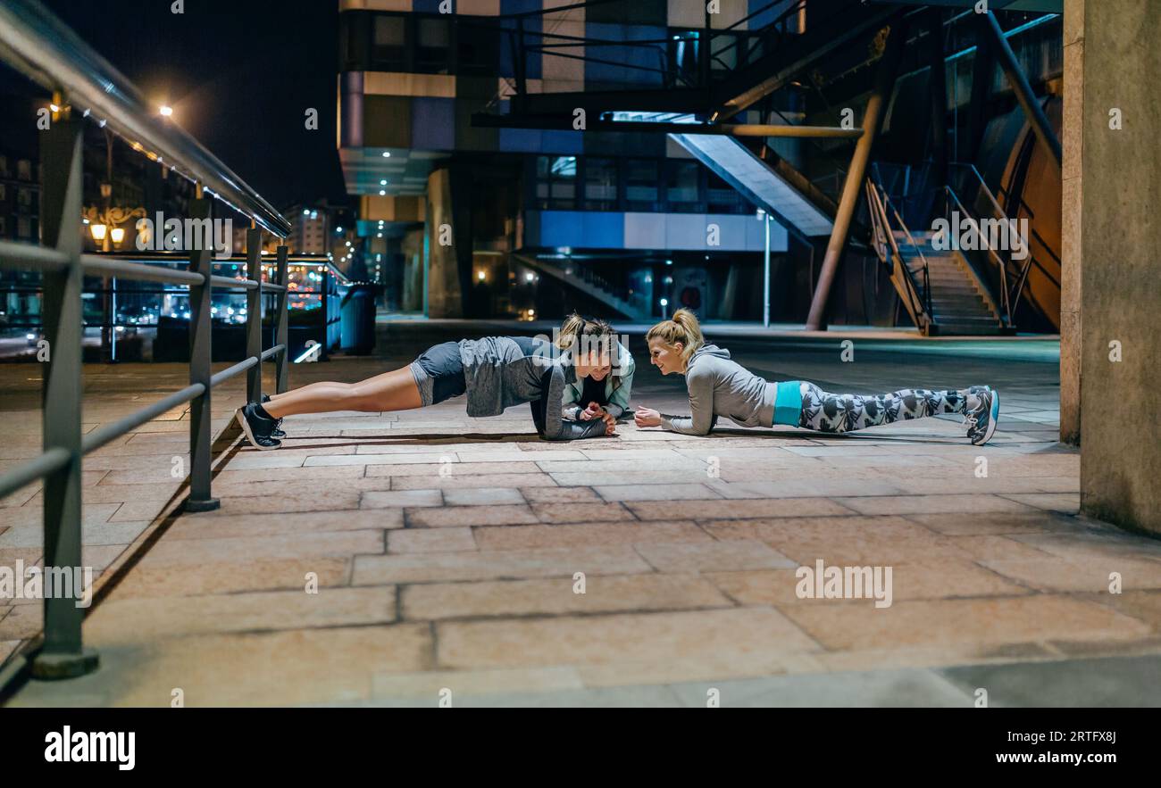 Women sport team doing plank exercise during training on the city at ...