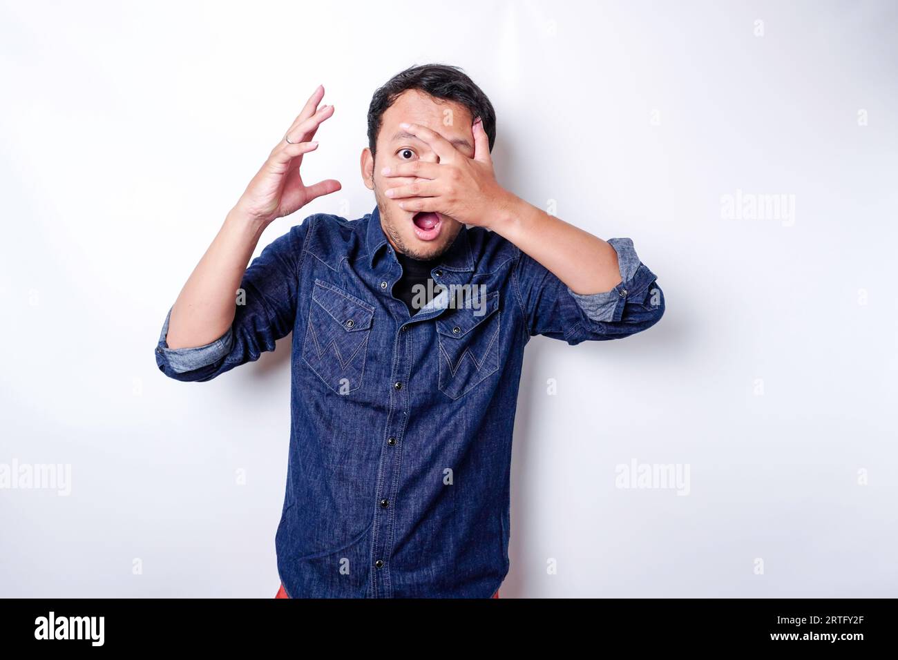 Funny obvious peeking Asian man in blue shirt isolated on white ...