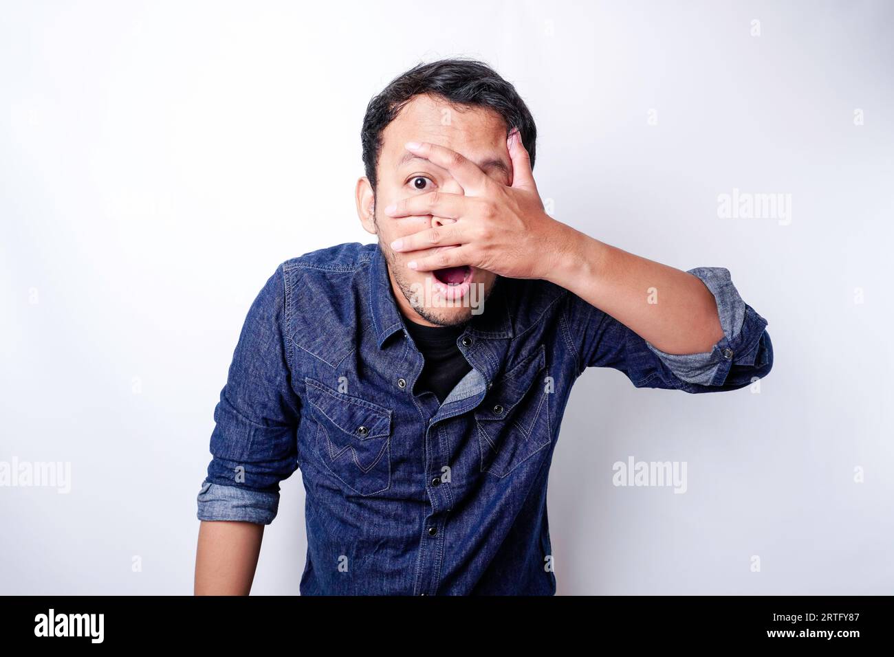 Funny obvious peeking Asian man in blue shirt isolated on white ...
