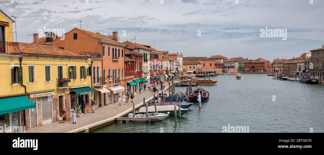 Murano, Italy - August 9, 2023; Perspective View of Venetian houses and boats along the canal at ...