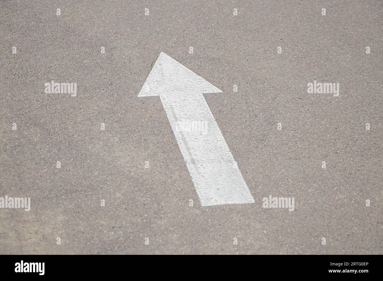 A white arrow pointing forward is drawn on the asphalt on the road as a ...