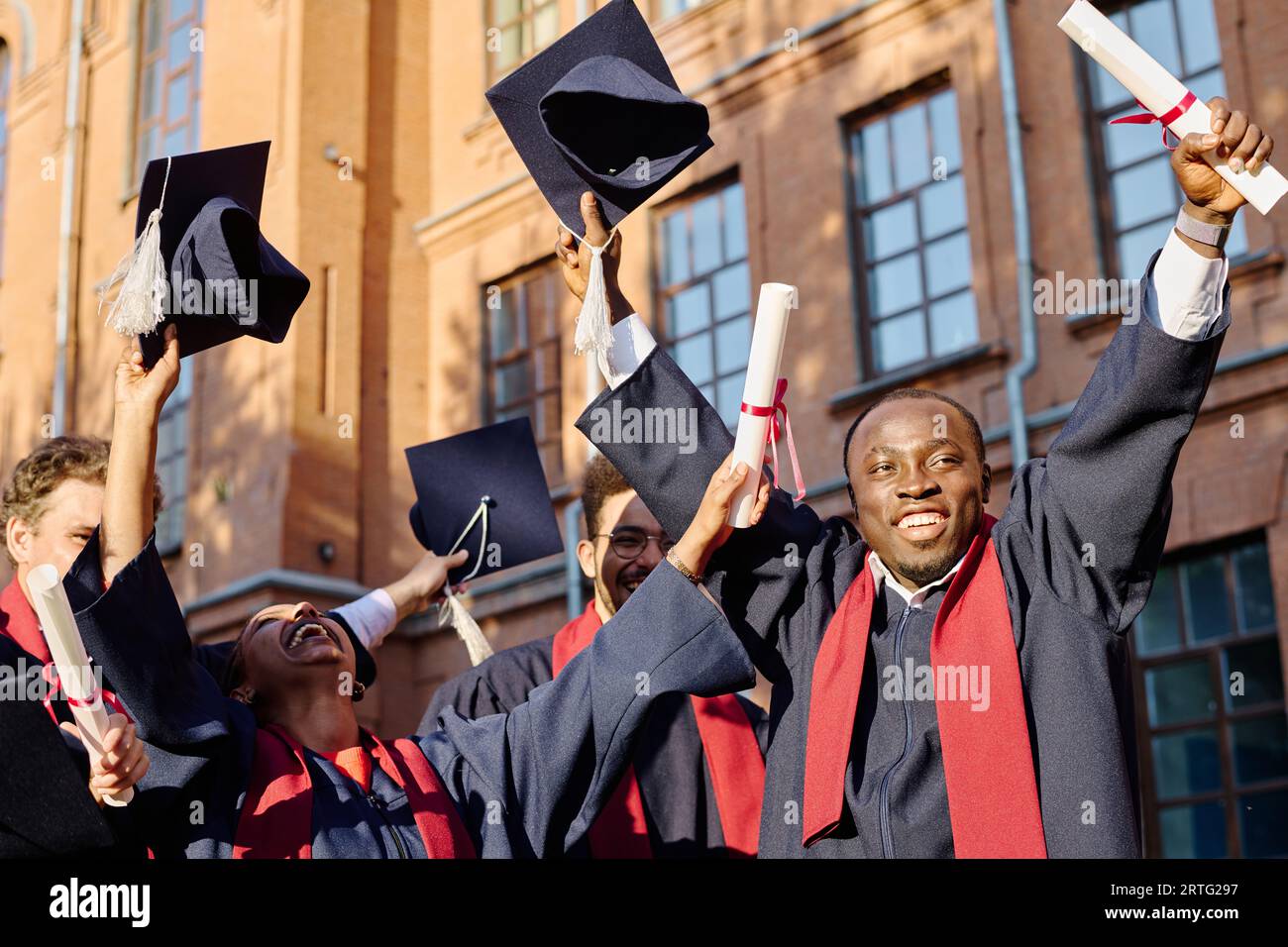 Group of excited multiethnic students in graduation gowns getting ...