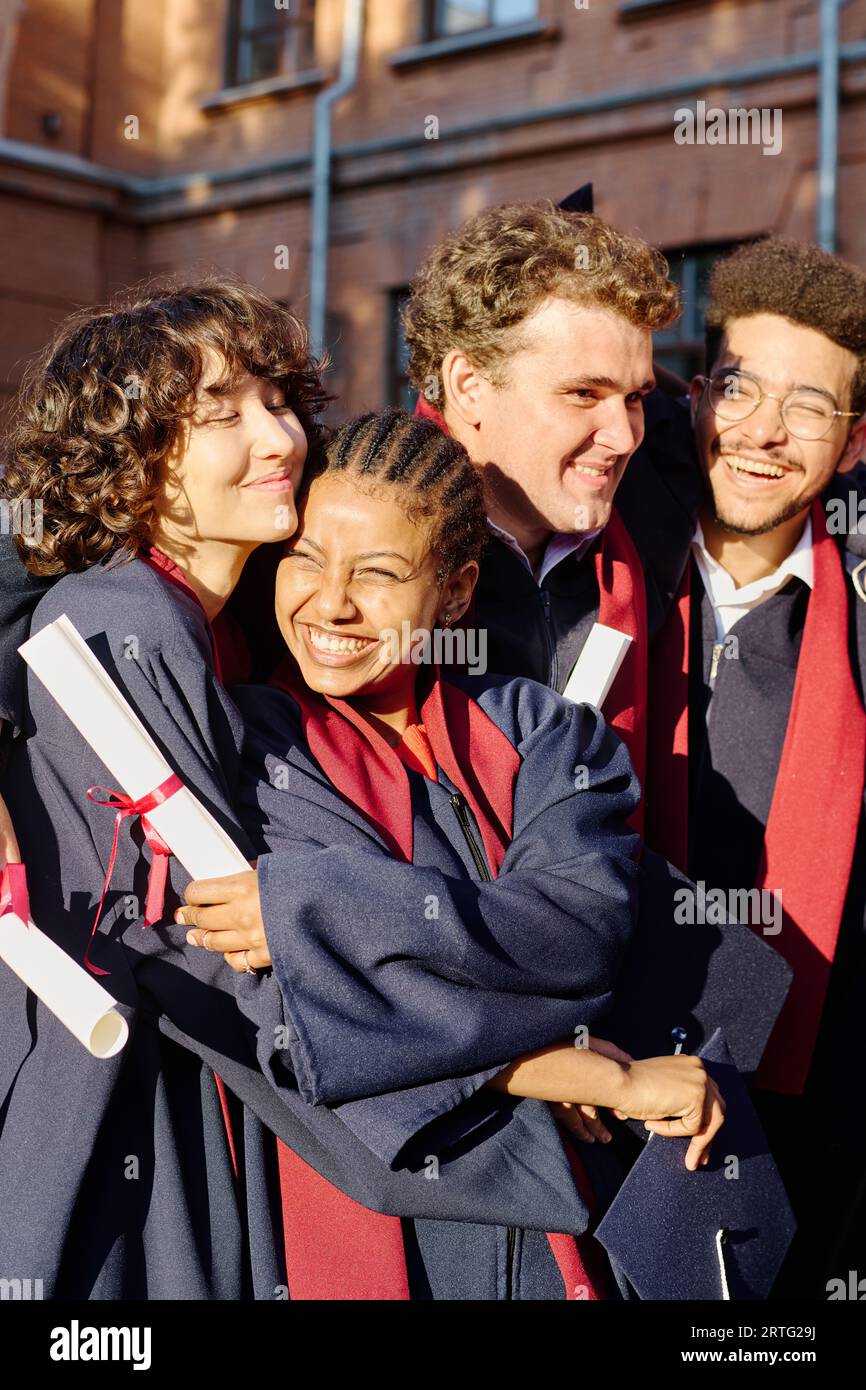 Vertical image of happy students embracing each other, they graduating ...