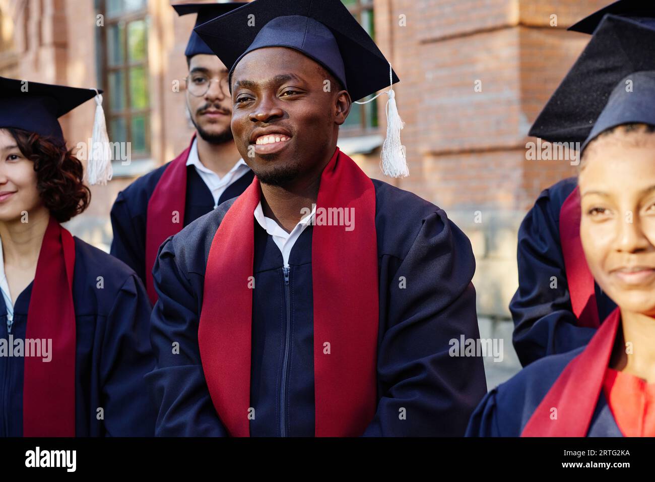 Multiethnic group of graduated students listening to speaker while ...