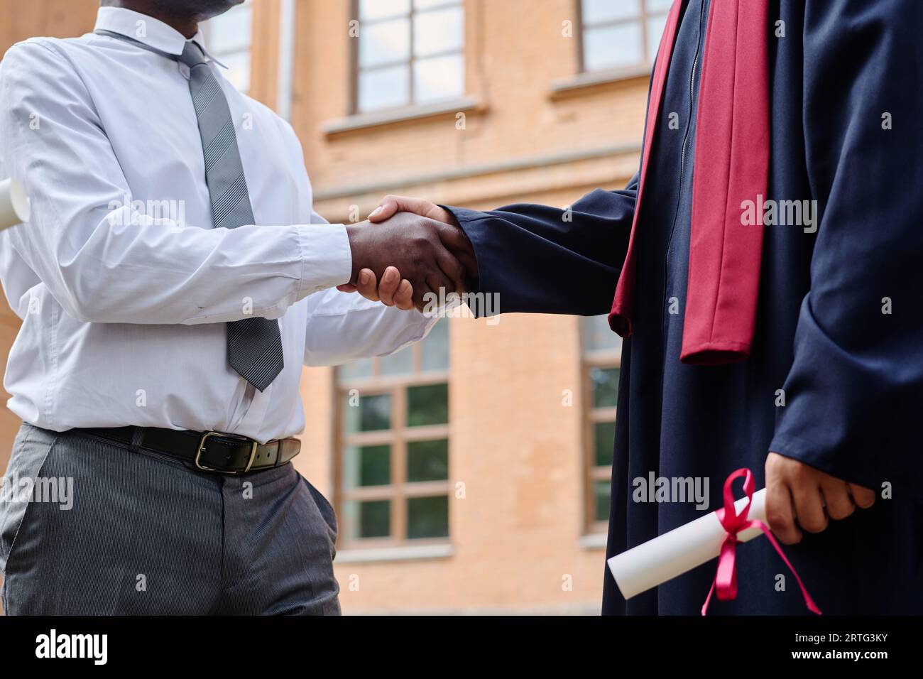 Close-up of African American teacher shaking hands with student, he ...
