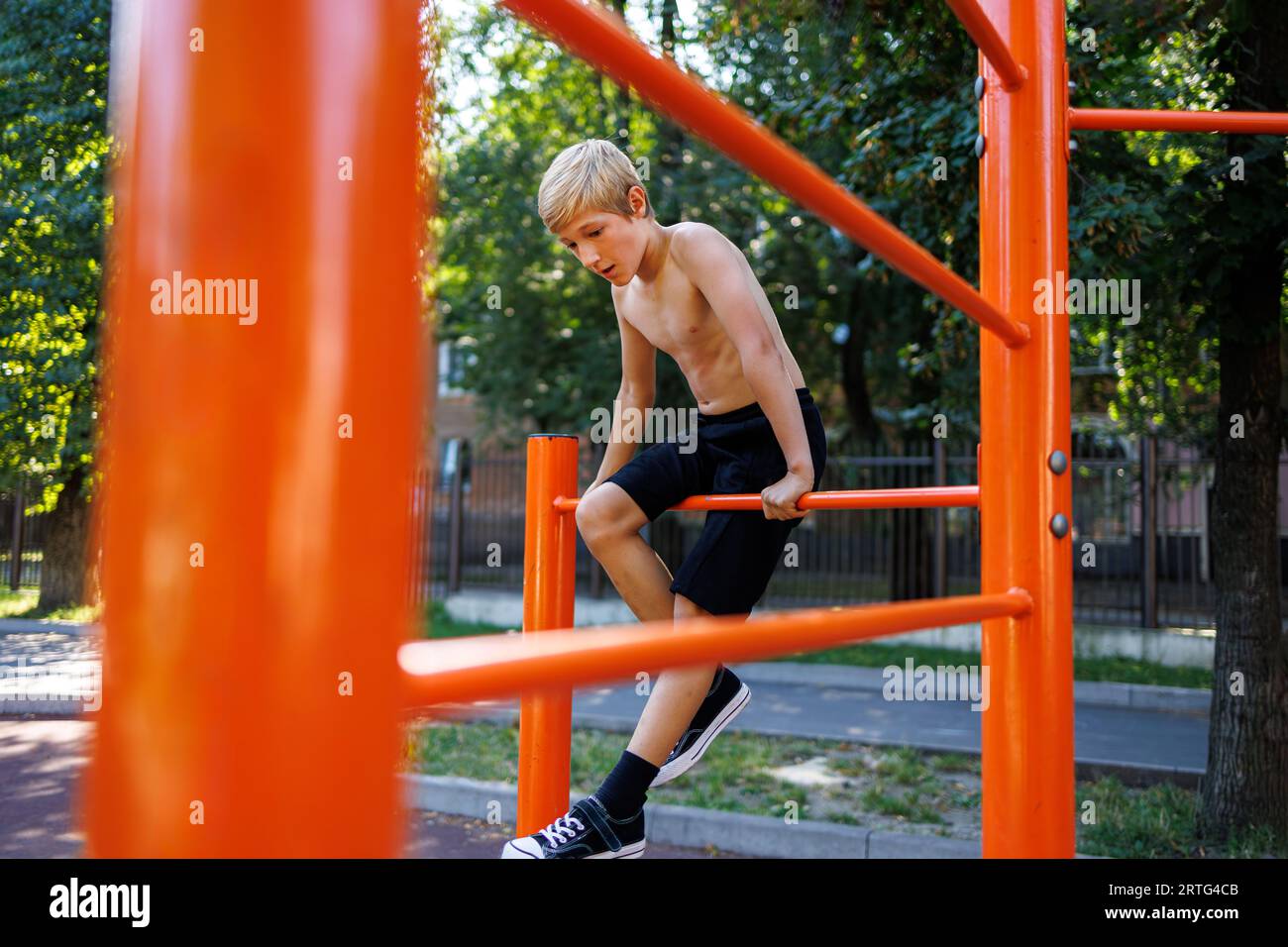 A fitness kid climbed between the gym bars. Street workout on a ...