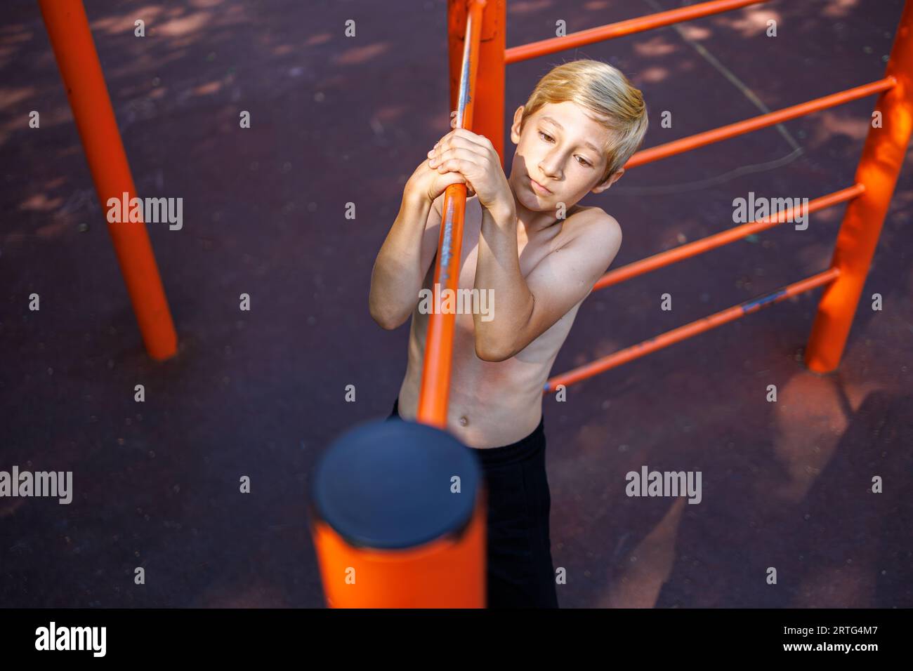 Sports child performs a side pull-up on the crossbar. Street workout on ...