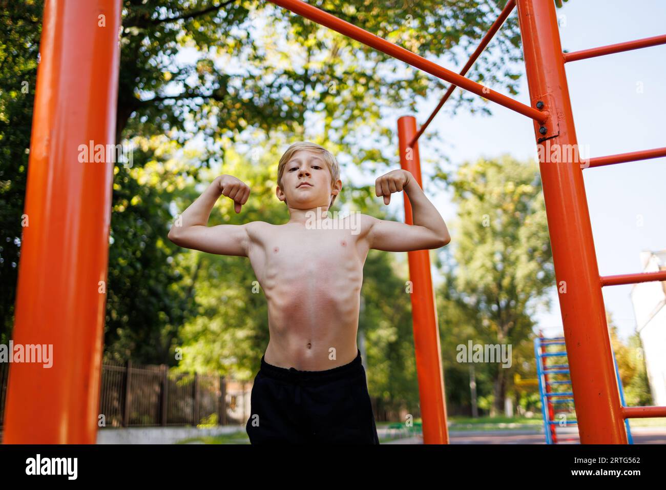 A teenager boy of an athletic build shows his muscles. Street workout ...