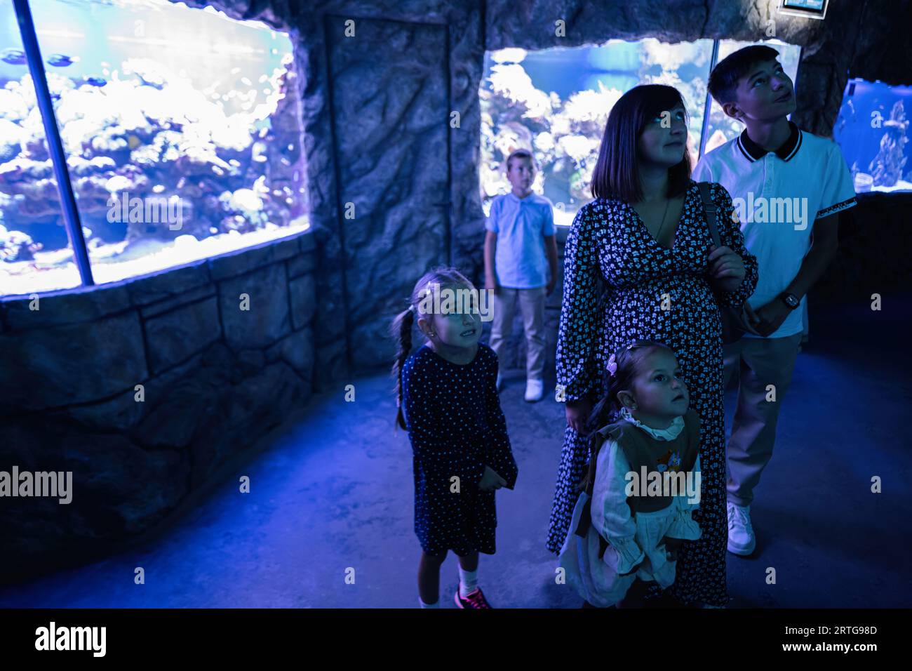 Family looking at fishes in oceanarium. Mother with children enjoying ...