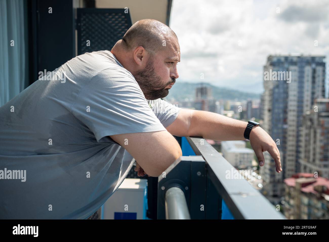 Overweight man feeling bad from heat in summer standing on balcony ...