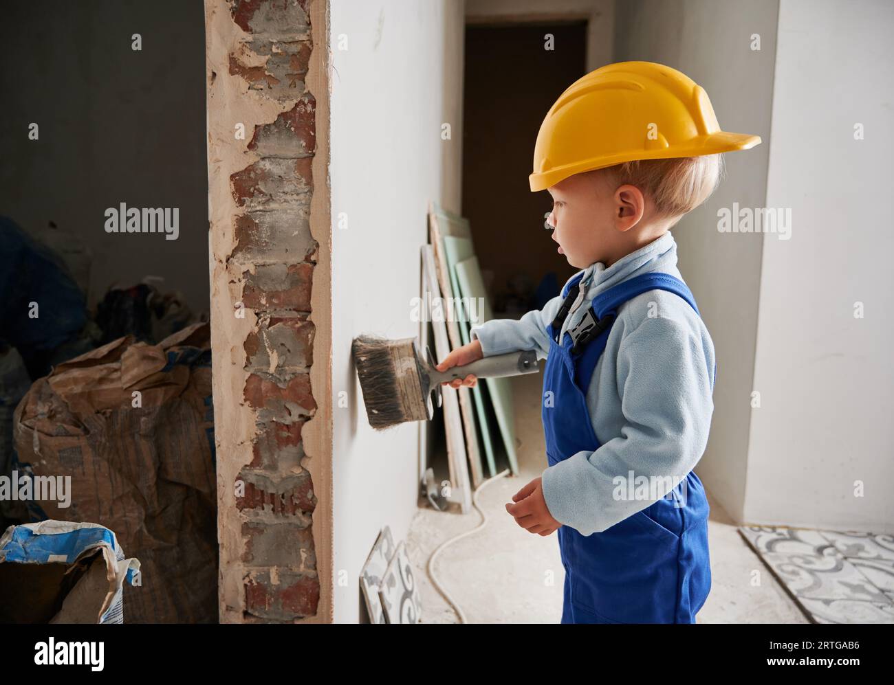 Side view of little boy construction worker using brush while working ...