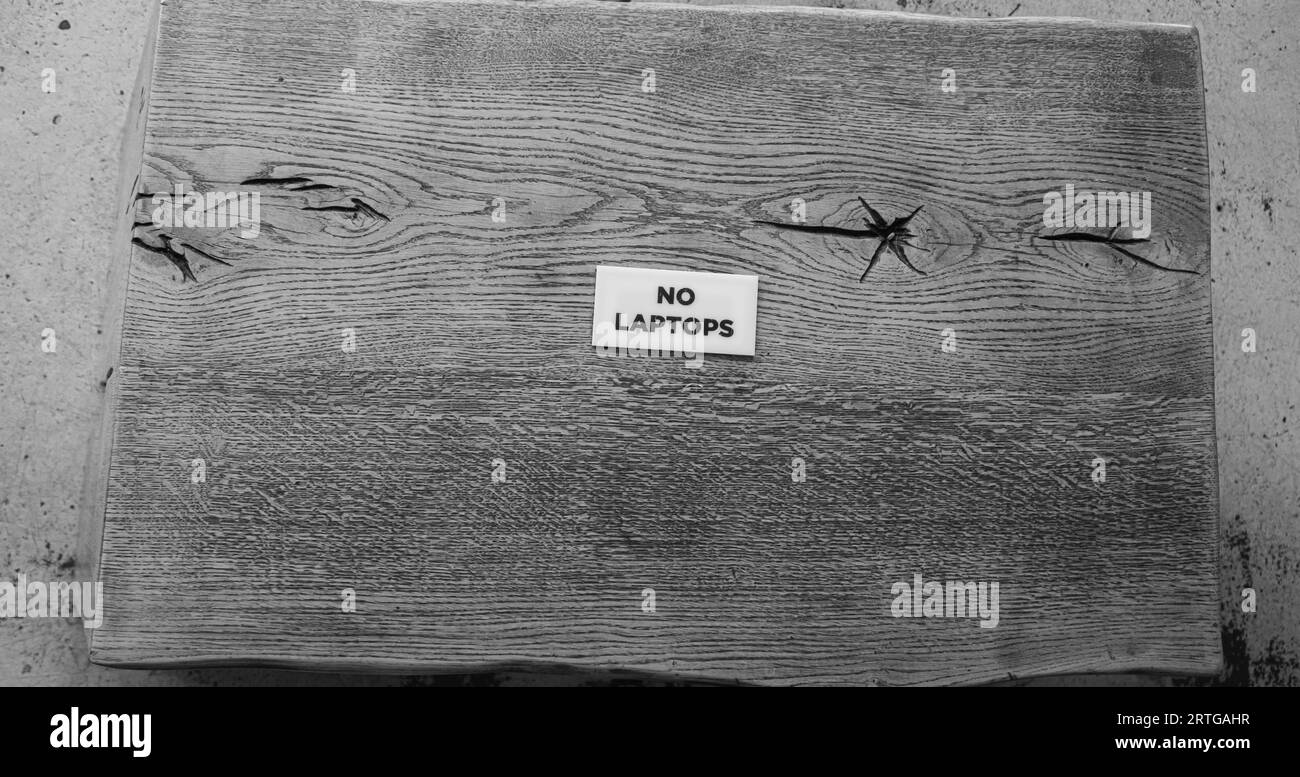 Wooden table with sign No Laptops, monochrome. No wi-fi zone in urban ...