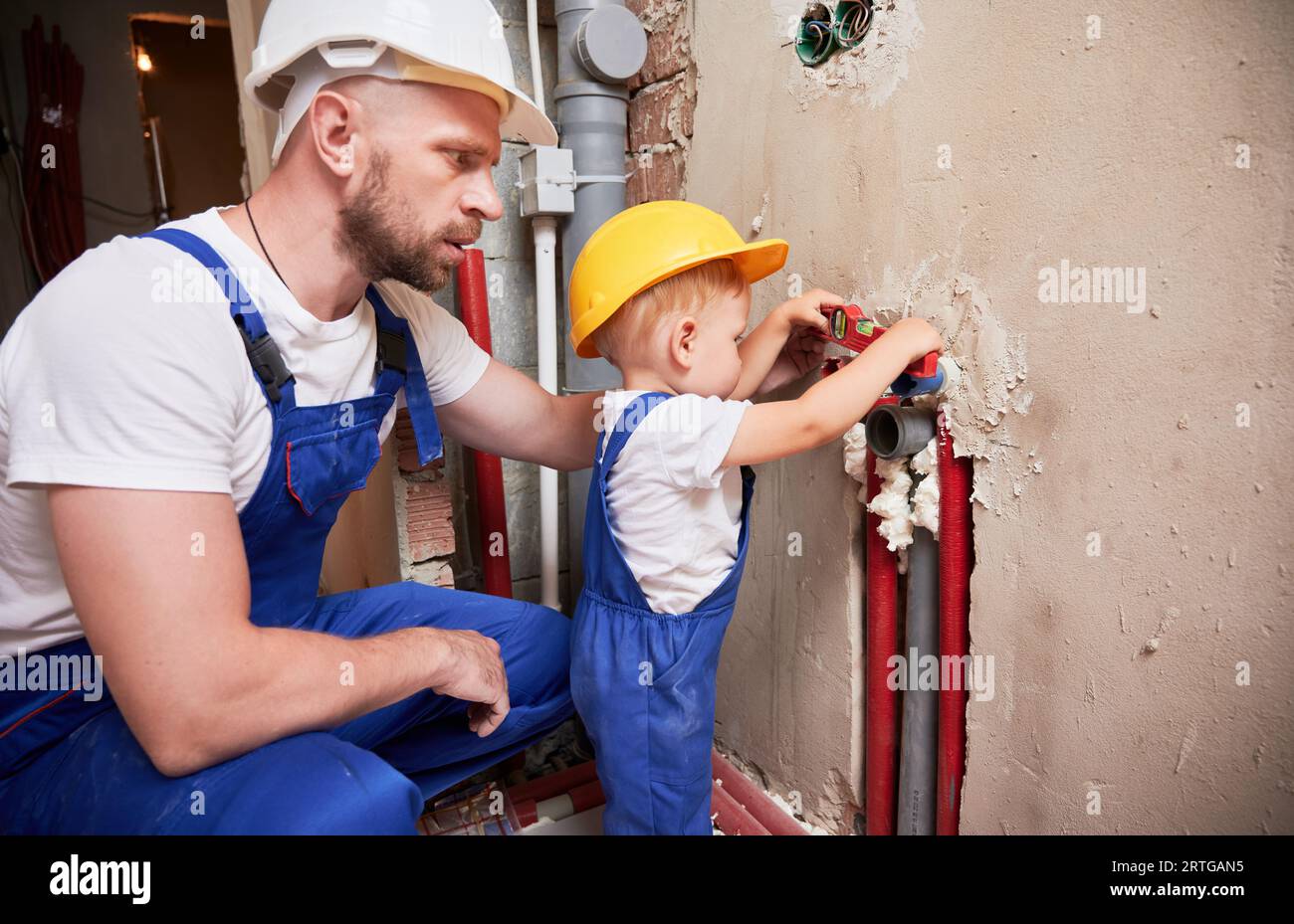 Father and son using spirit level tool while installing plumbing pipes ...
