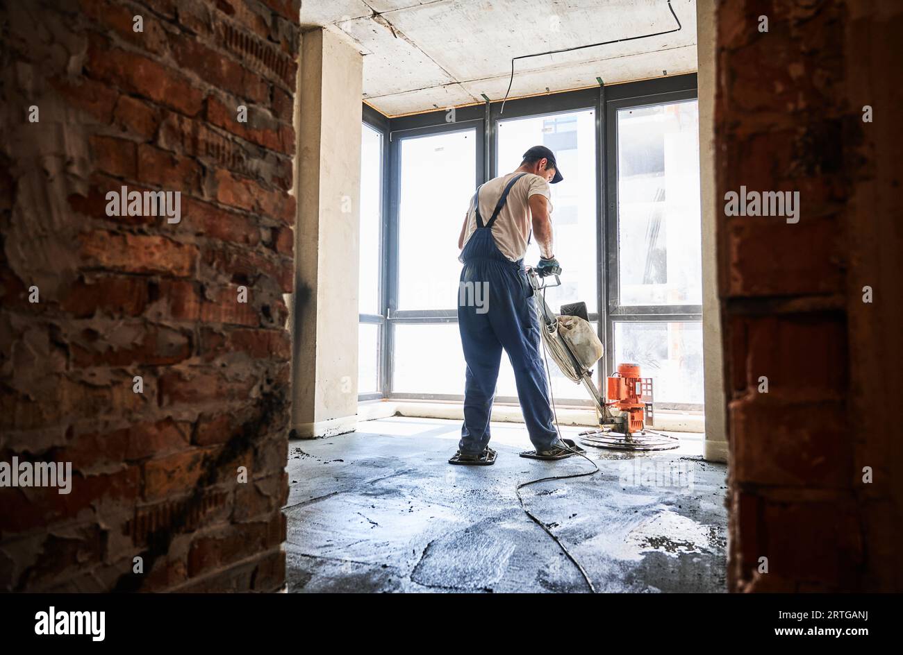 Man finishing concrete surface with floor screed grinder machine in ...