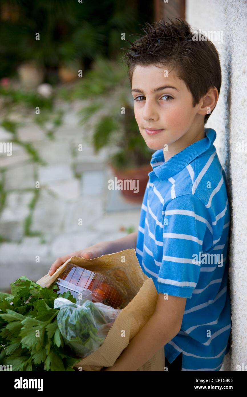Young boy holding a brown paper bag full of fruit and vegetables Stock ...