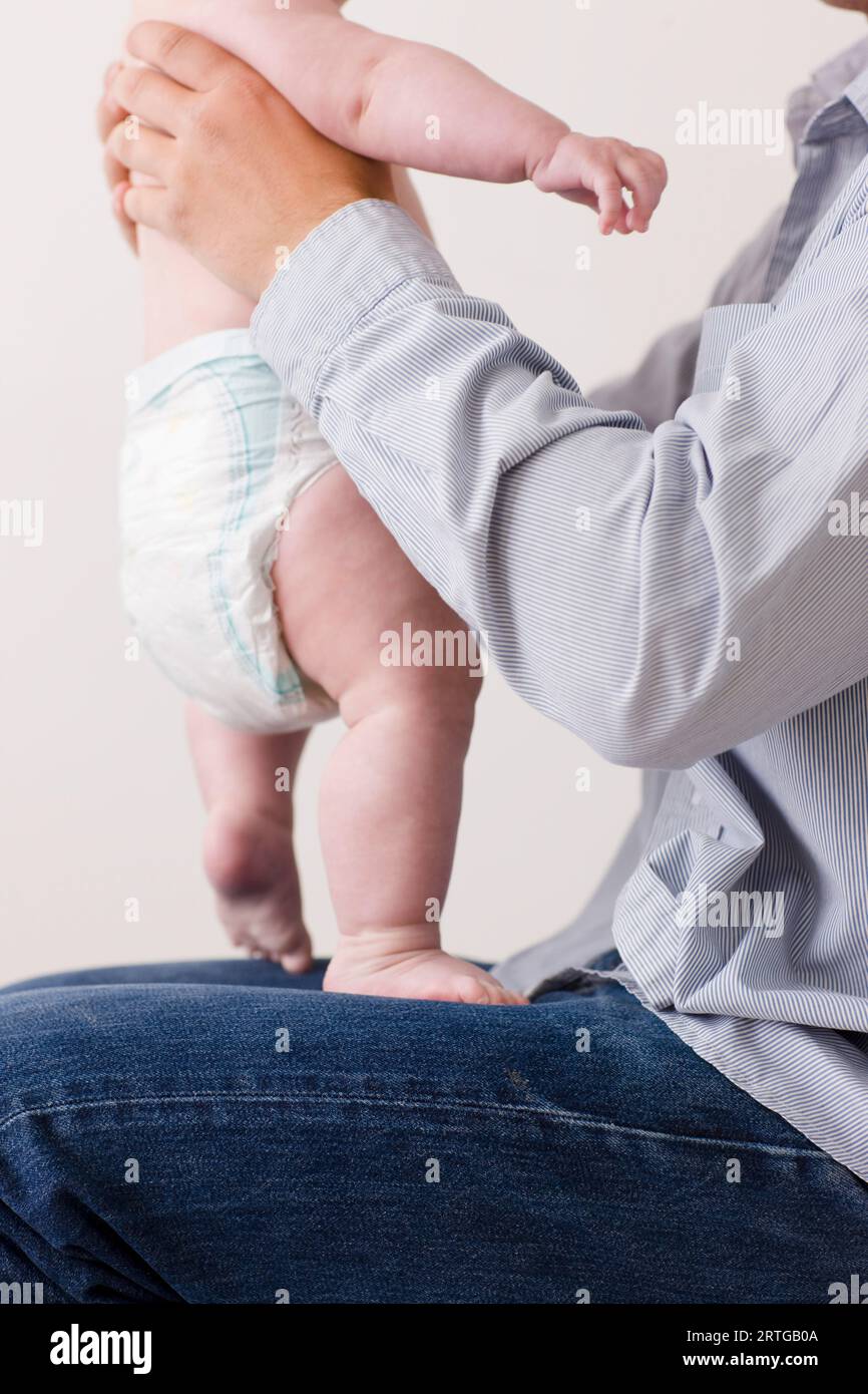 Man sitting with newborn baby standing on his lap Stock Photo - Alamy