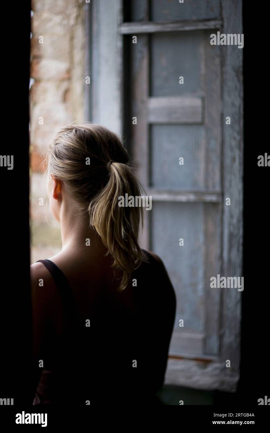 Back view of a woman looking out of a window Stock Photo - Alamy