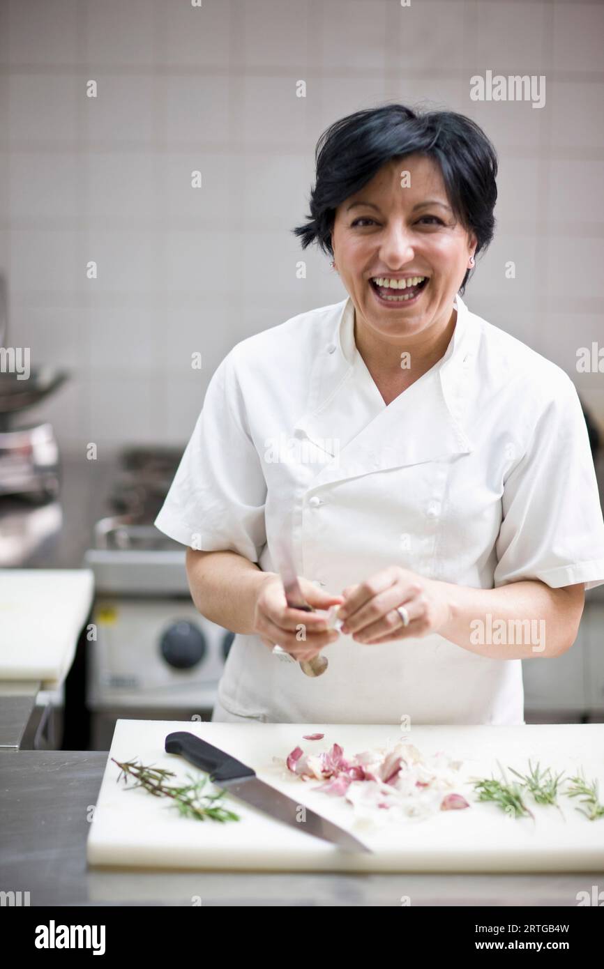Woman chef peeling garlic with a knife and smiling Stock Photo - Alamy