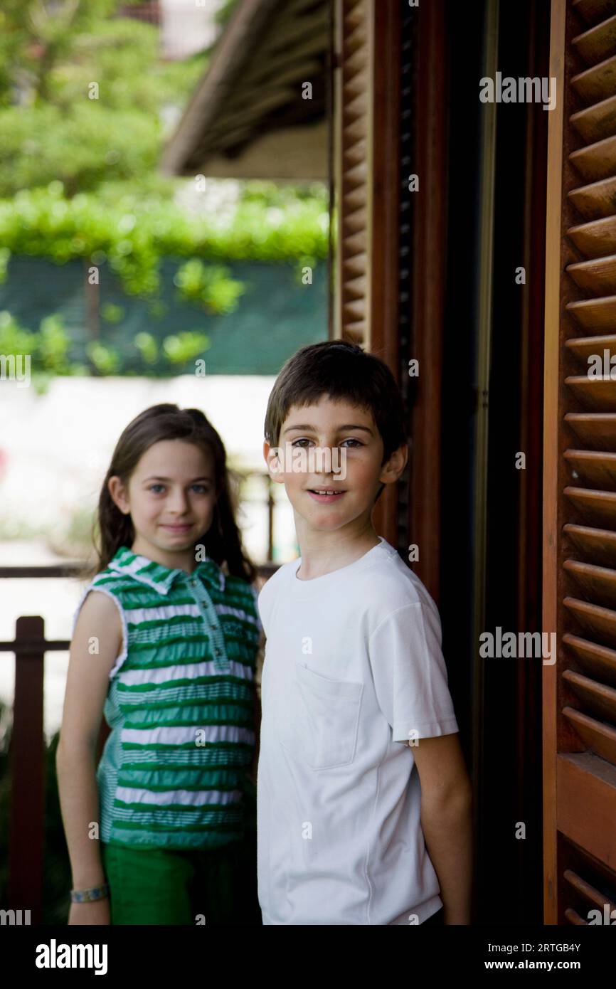 Young boy and young girl standing by window with wooden shutters Stock Photo - Alamy