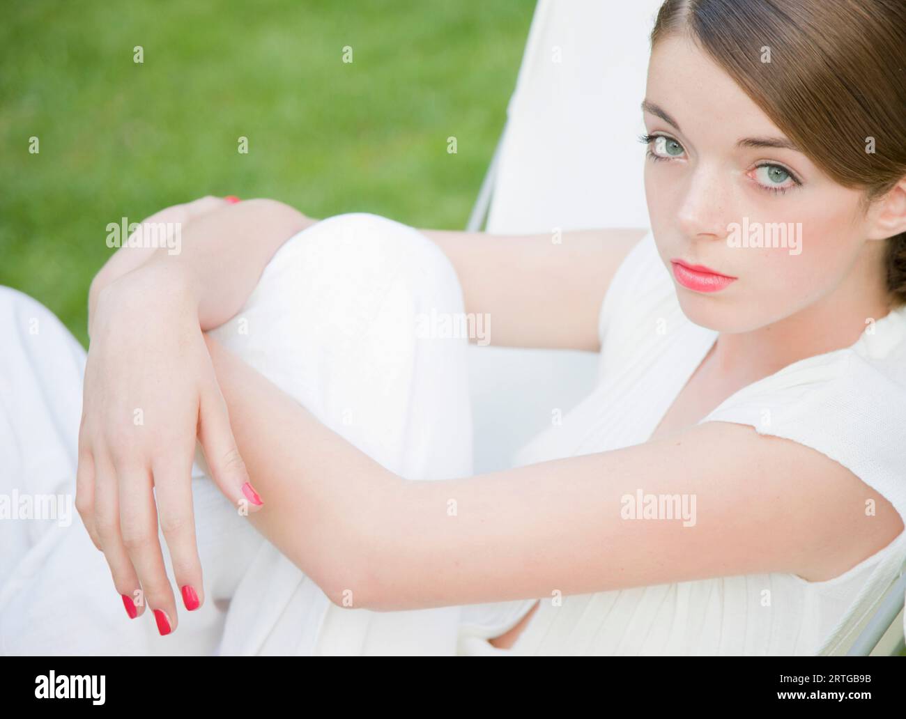Teenaged girl sitting with arms around knees Stock Photo - Alamy