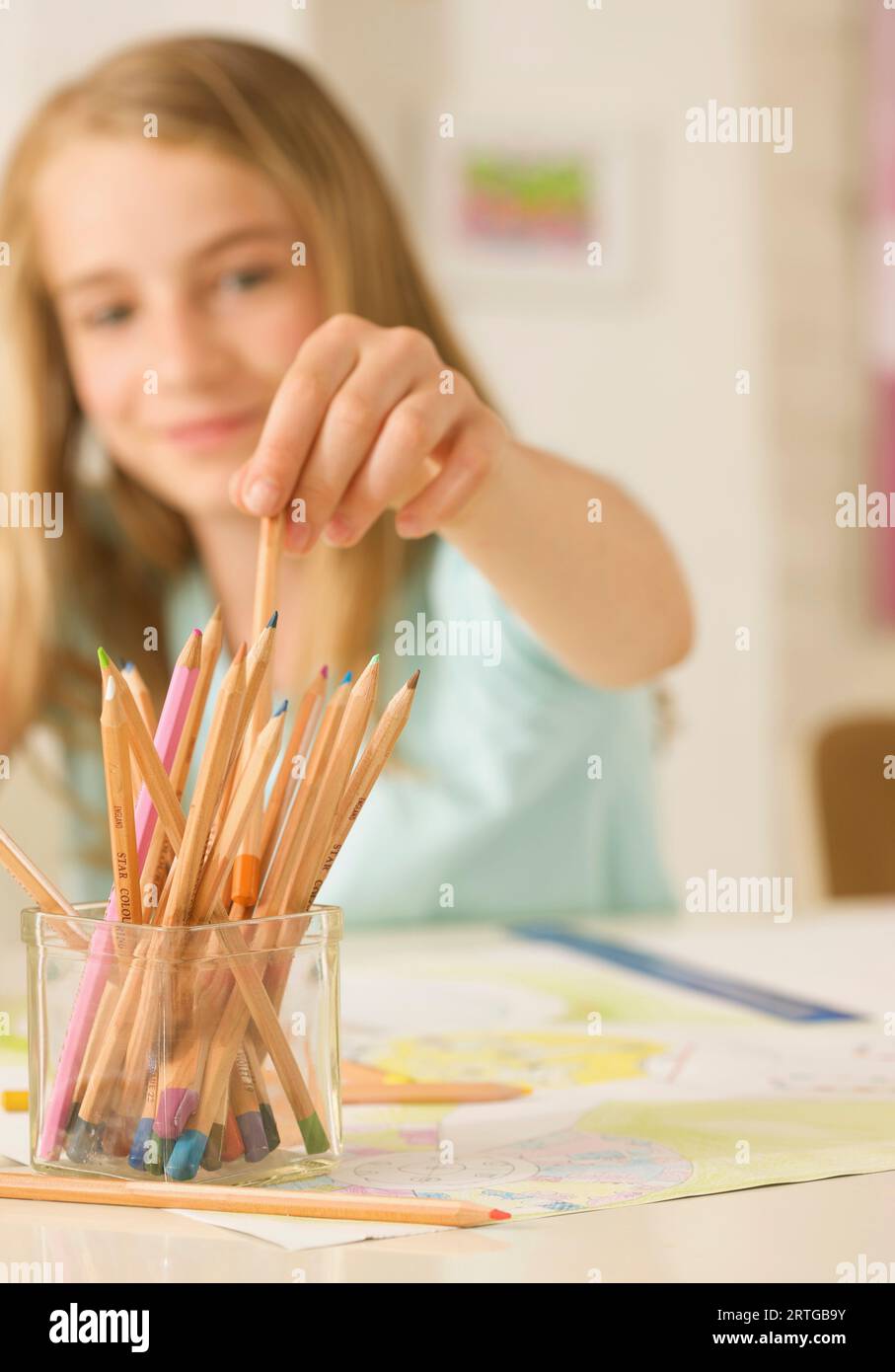 Young girl choosing a coloring pencil from container Stock Photo - Alamy