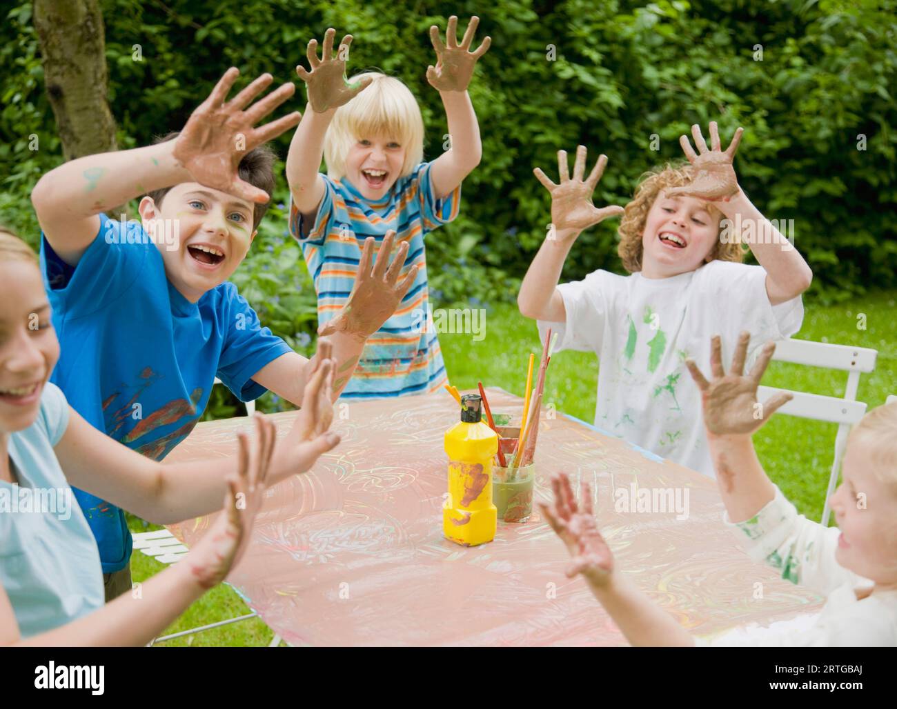 Children smiling and laughing with their arms up and hands covered in ...
