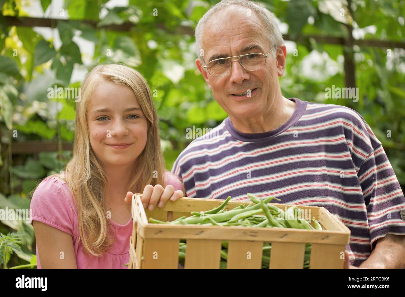 Young girl and mature man holding a crate of broad beans Stock Photo ...