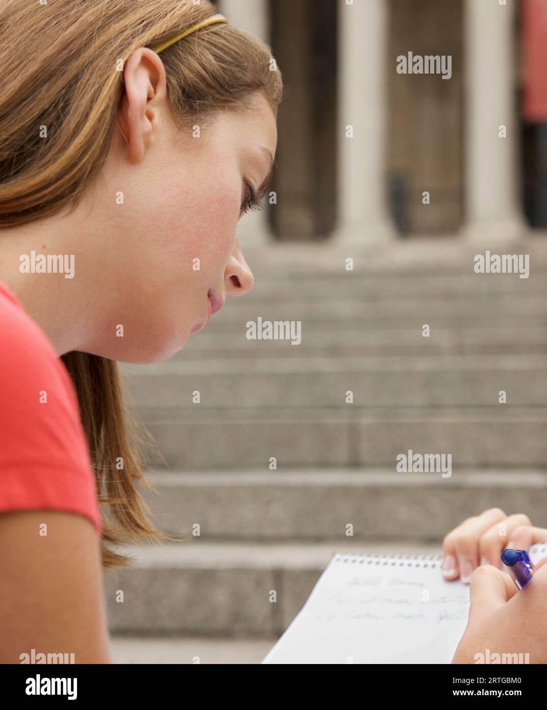 Teenaged girl taking notes opposite a city building Stock Photo - Alamy