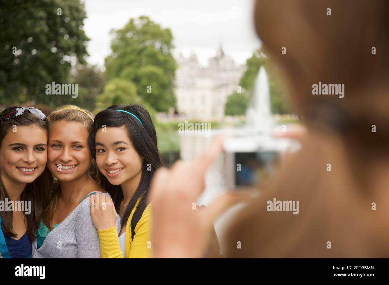 Back view of a woman taking photograph of three teenaged girls Stock ...