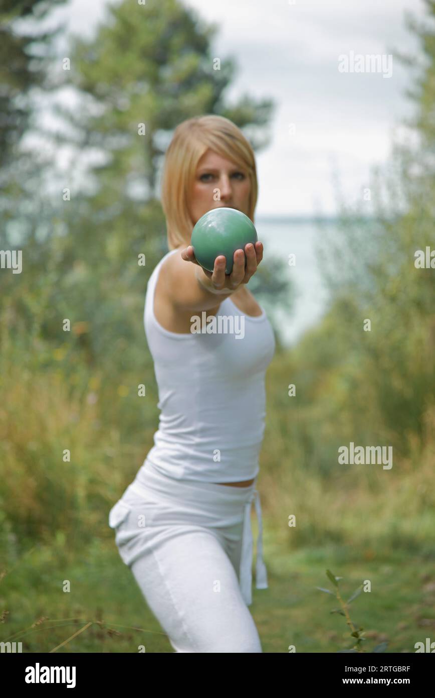Young woman stretching and balancing a sphere in one hand Stock Photo ...