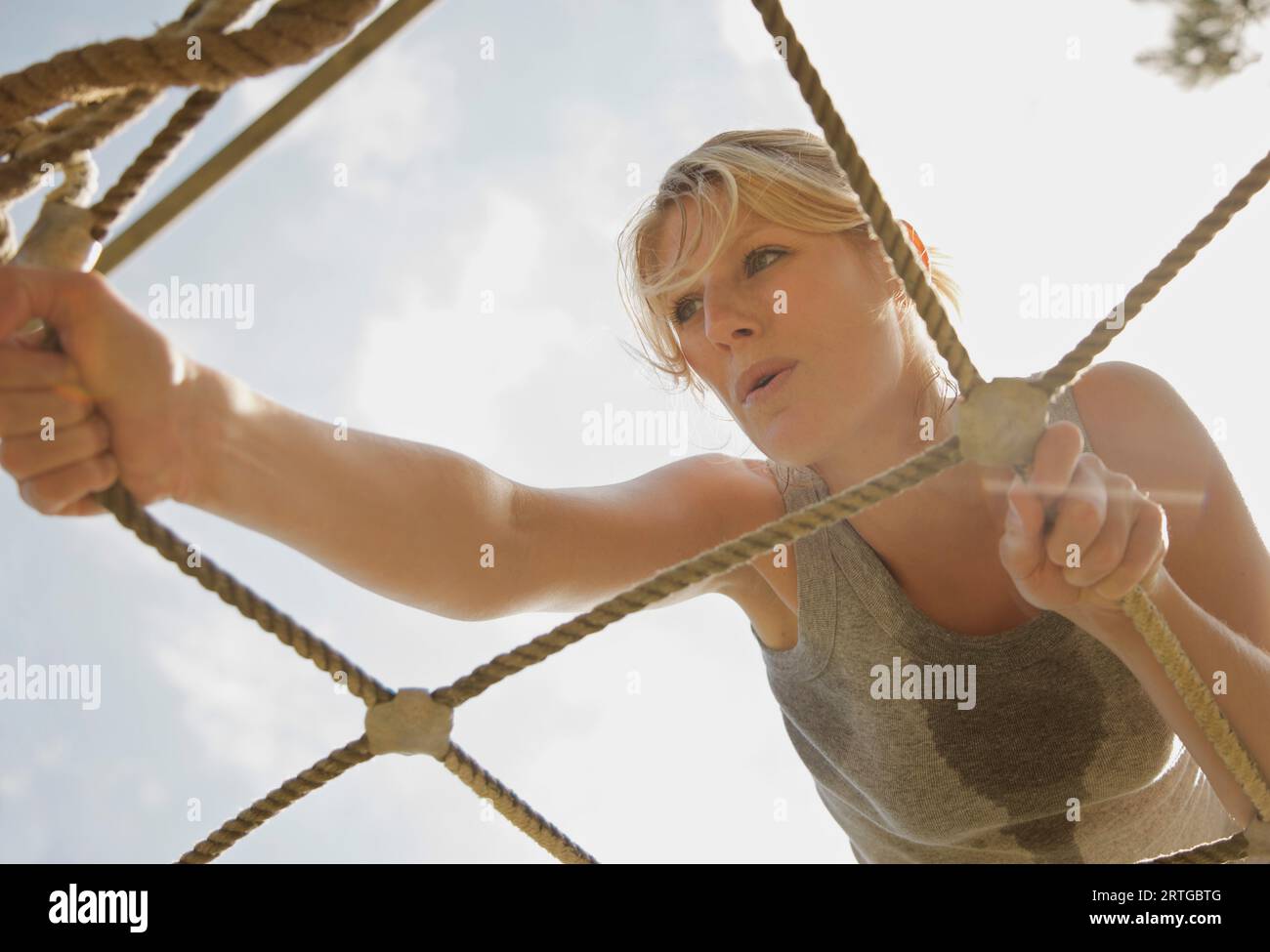 Young woman at obstacle course climbing a cargo net Stock Photo - Alamy