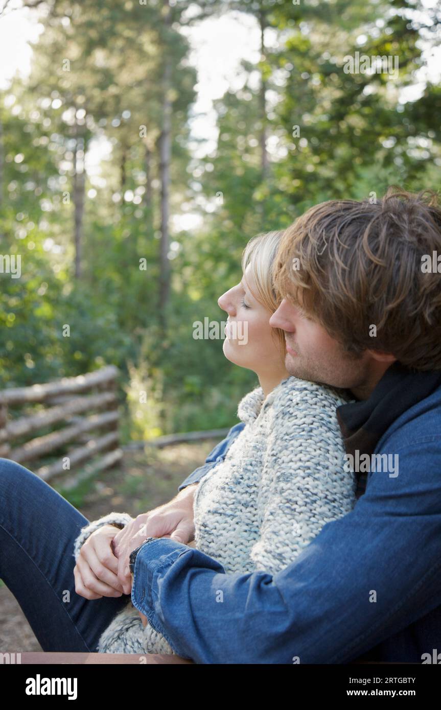 Profile of a young couple sitting and hugging Stock Photo - Alamy