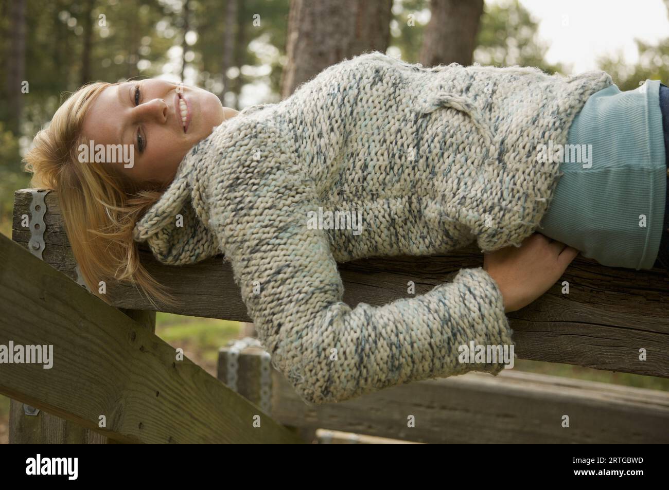 Young woman lying on a wooden beam smiling Stock Photo - Alamy