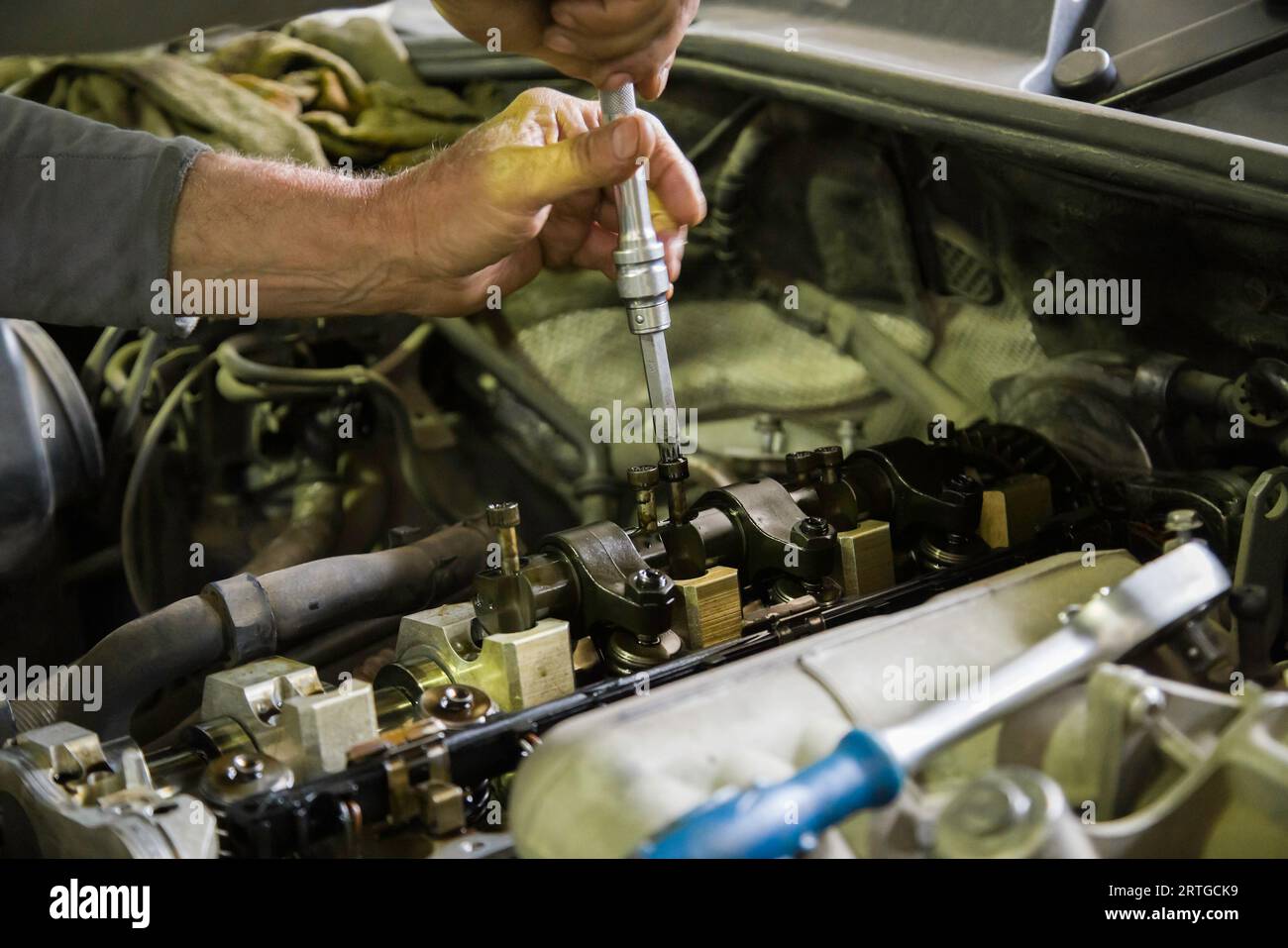 hands of mechanic screwing or unscrewing rocker arm shaft of combustion ...