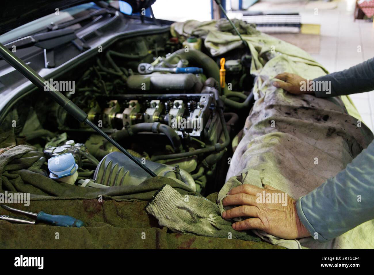 mechanic hands rests on an edge of motor compartment with combustion ...