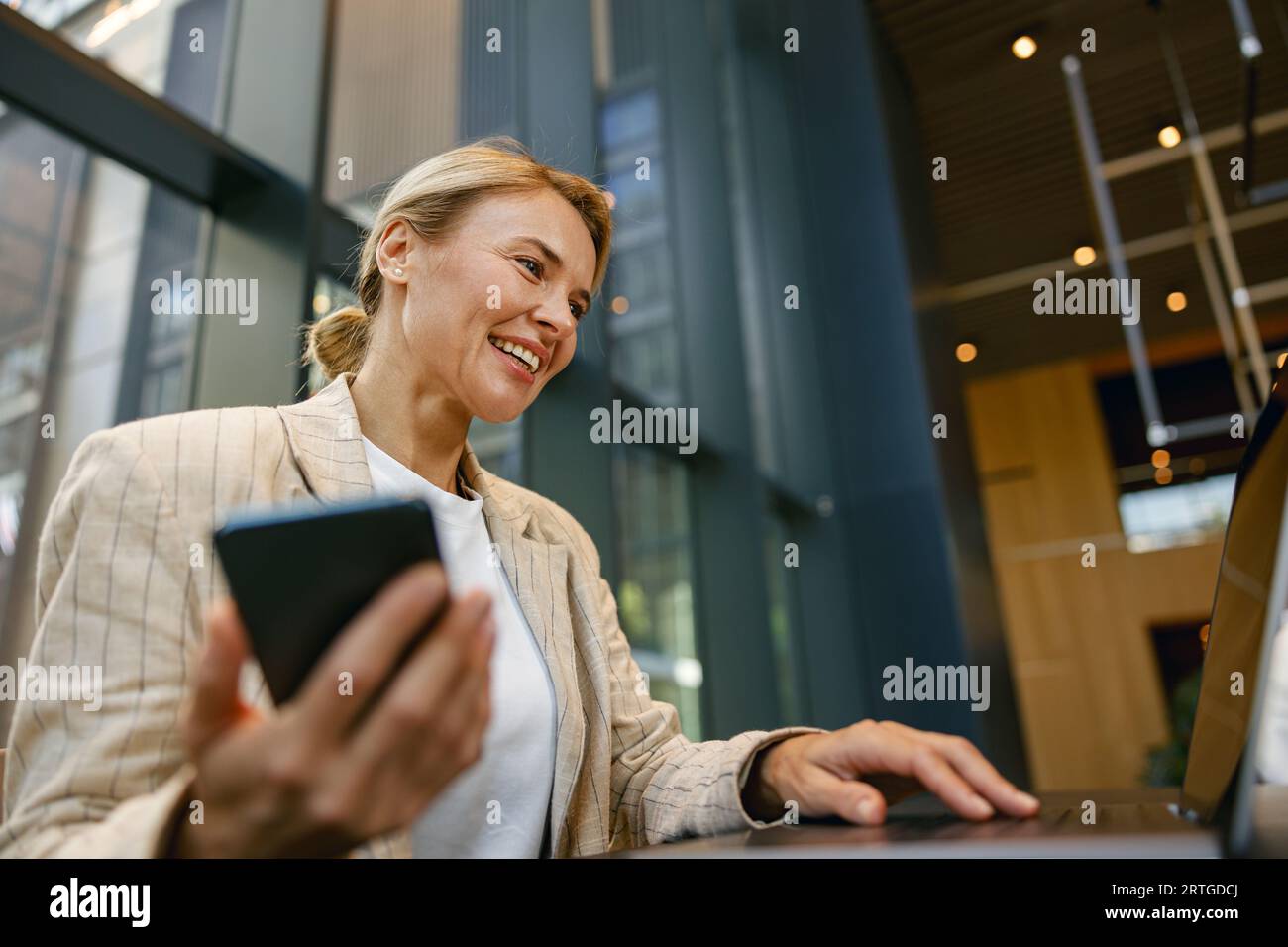 Close up of female entrepreneur use phone while working on laptop in ...