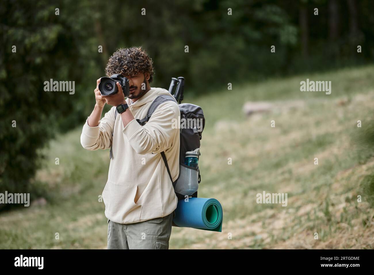 curly indian tourist taking photo on professional camera, hiker with ...