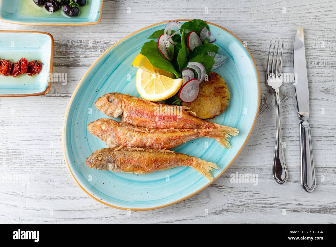 Delicious grilled red mullet fish with garnishes like lemon, greens and ...