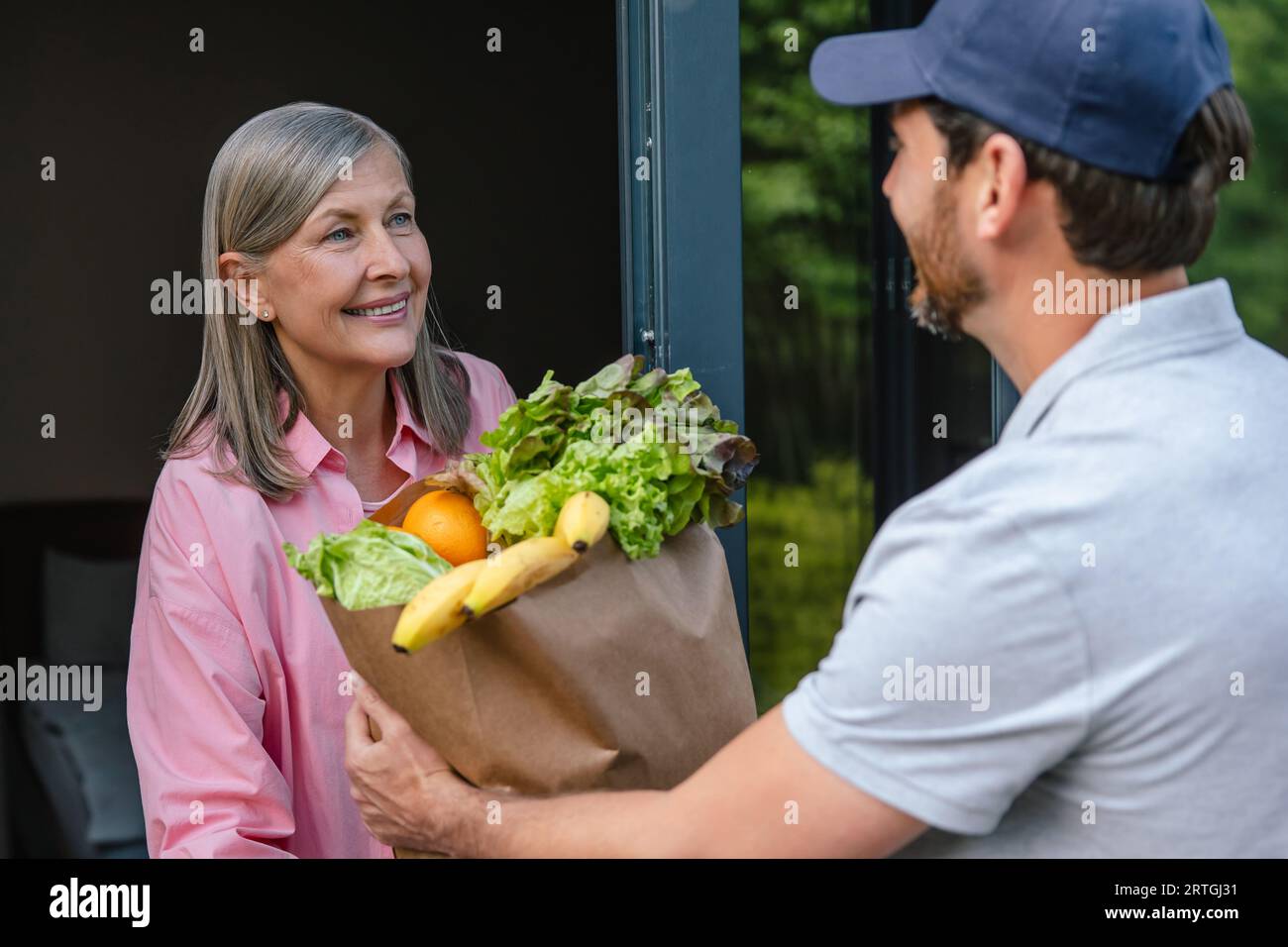 Grocery store delivery man delivering food to woman home Stock Photo ...