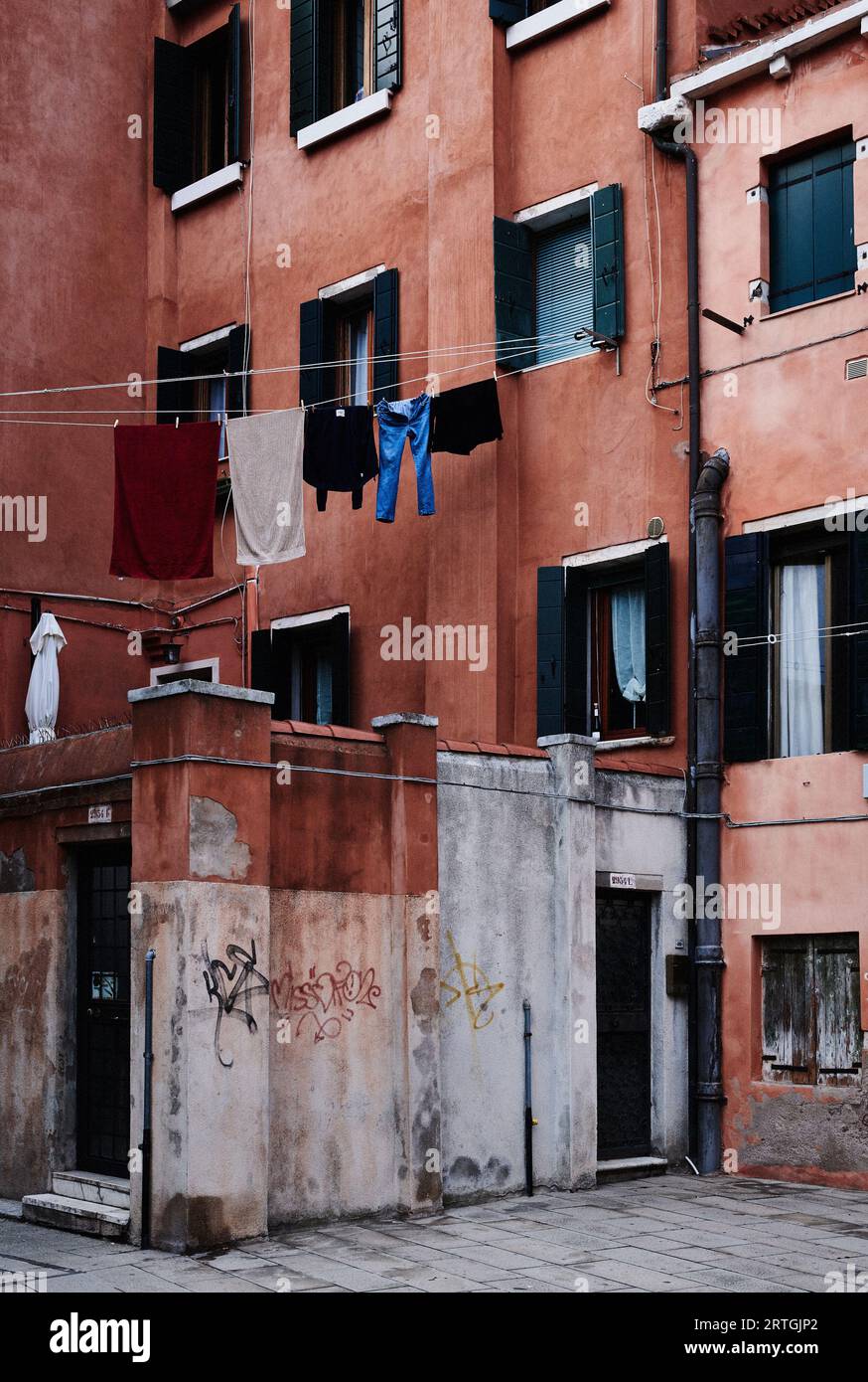 Muted red residential building with green shuttered windows. Washing ...