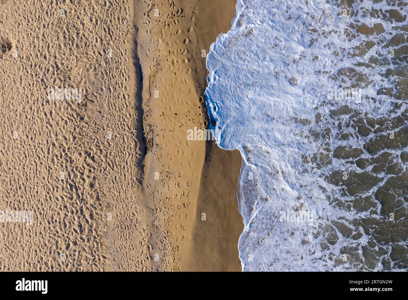 Aerial view of ocean waves washing a secluded sandy shoreline beach ...