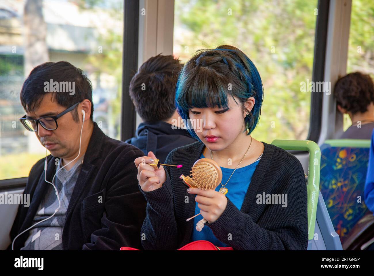 Commuter doing her makeup in the morning on a suburban train on the way ...