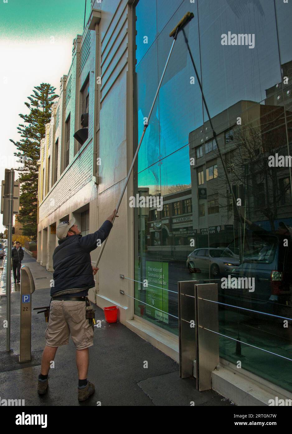 A window cleaner using a long flexible pole to clean office windows in ...
