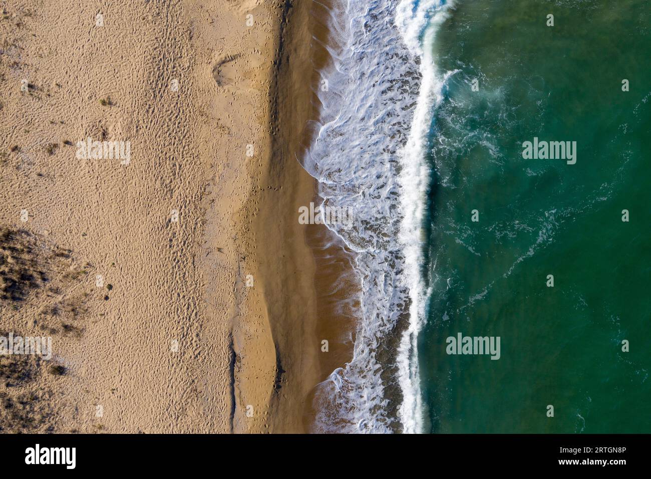 Aerial view of ocean waves washing a secluded sandy shoreline beach ...