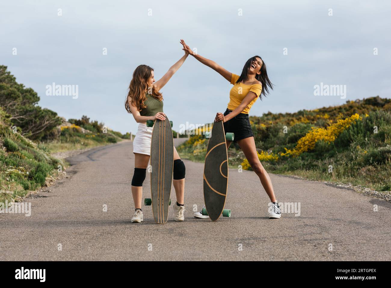 Full body of happy multiethnic girlfriends giving high five while ...