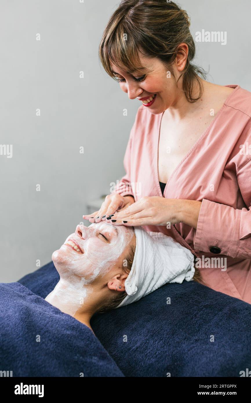 Female cosmetician applying facial cleanser on face of female client ...