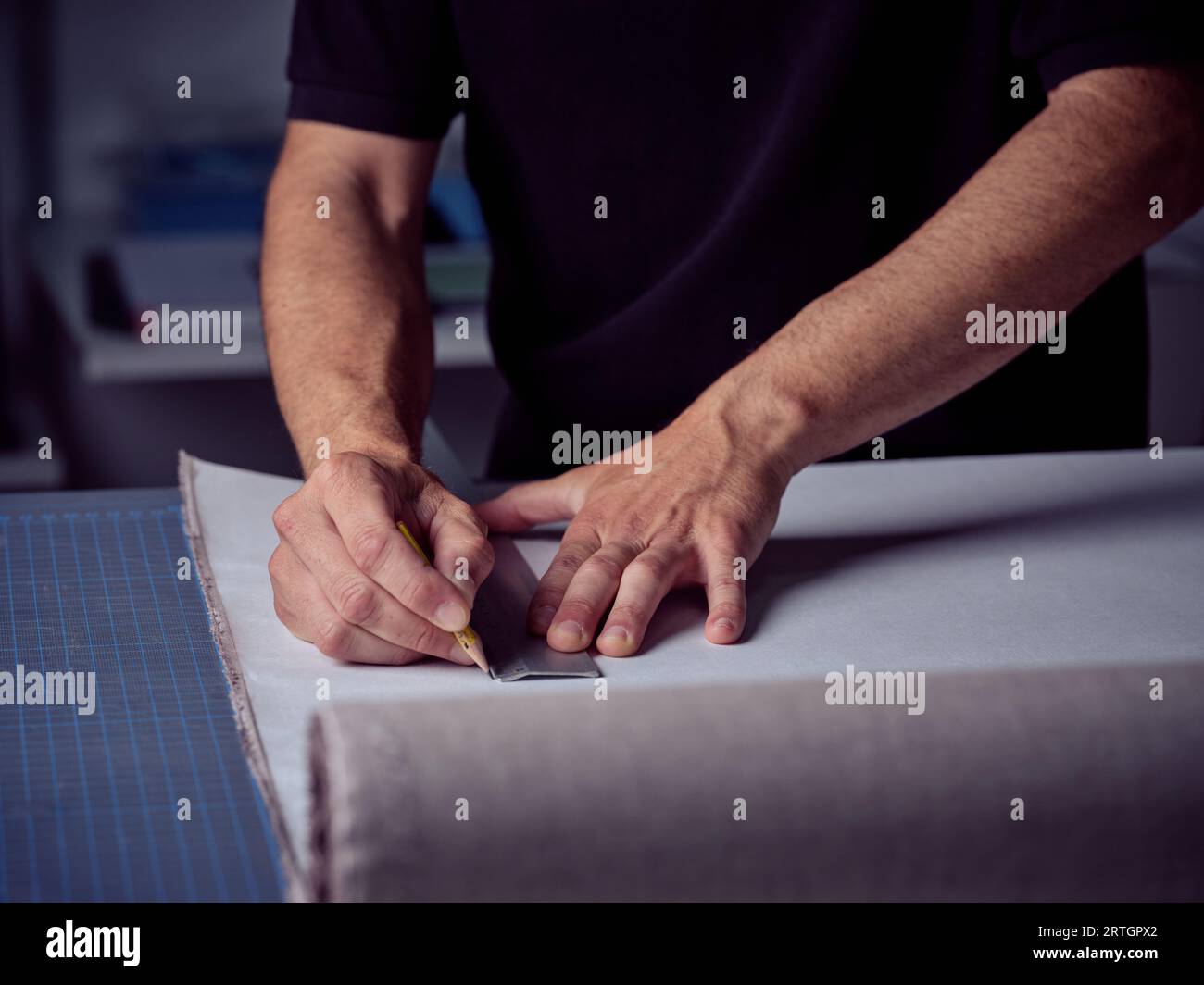 Crop male bookbinder making marks on paper while using pencil and ruler ...