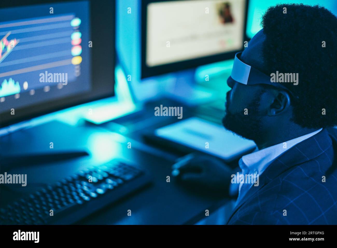 African trader working inside office at night time wearing virtual reality headset - Trading and ...